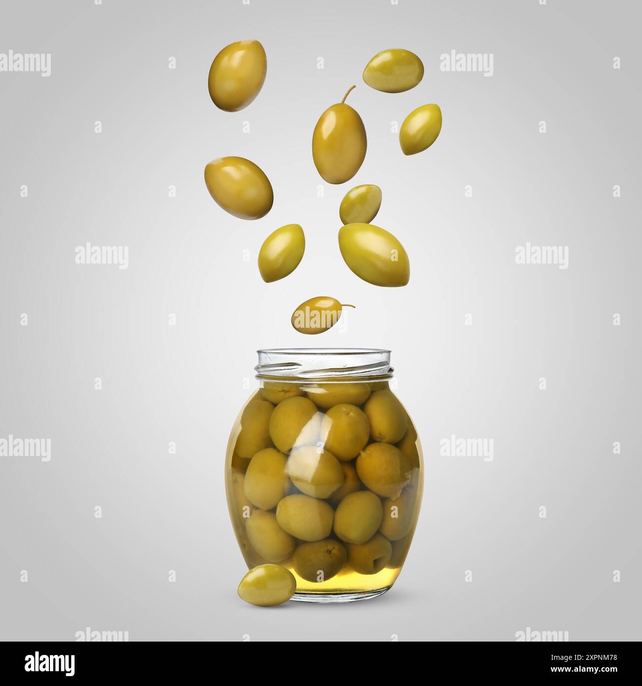 Olives falling into jar on light grey background Stock Photo - Alamy