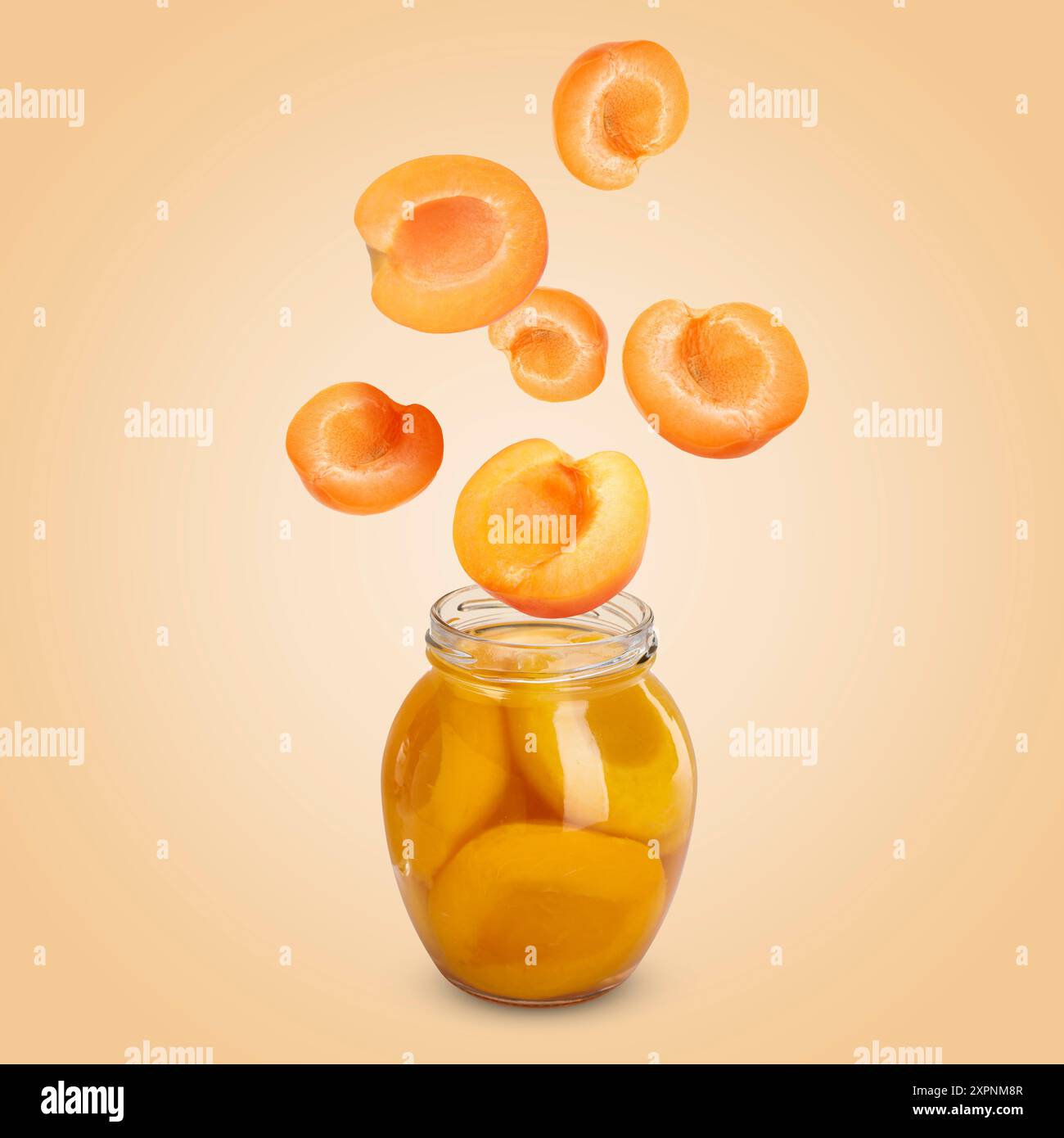 Apricots falling into jar on pale orange background Stock Photo - Alamy