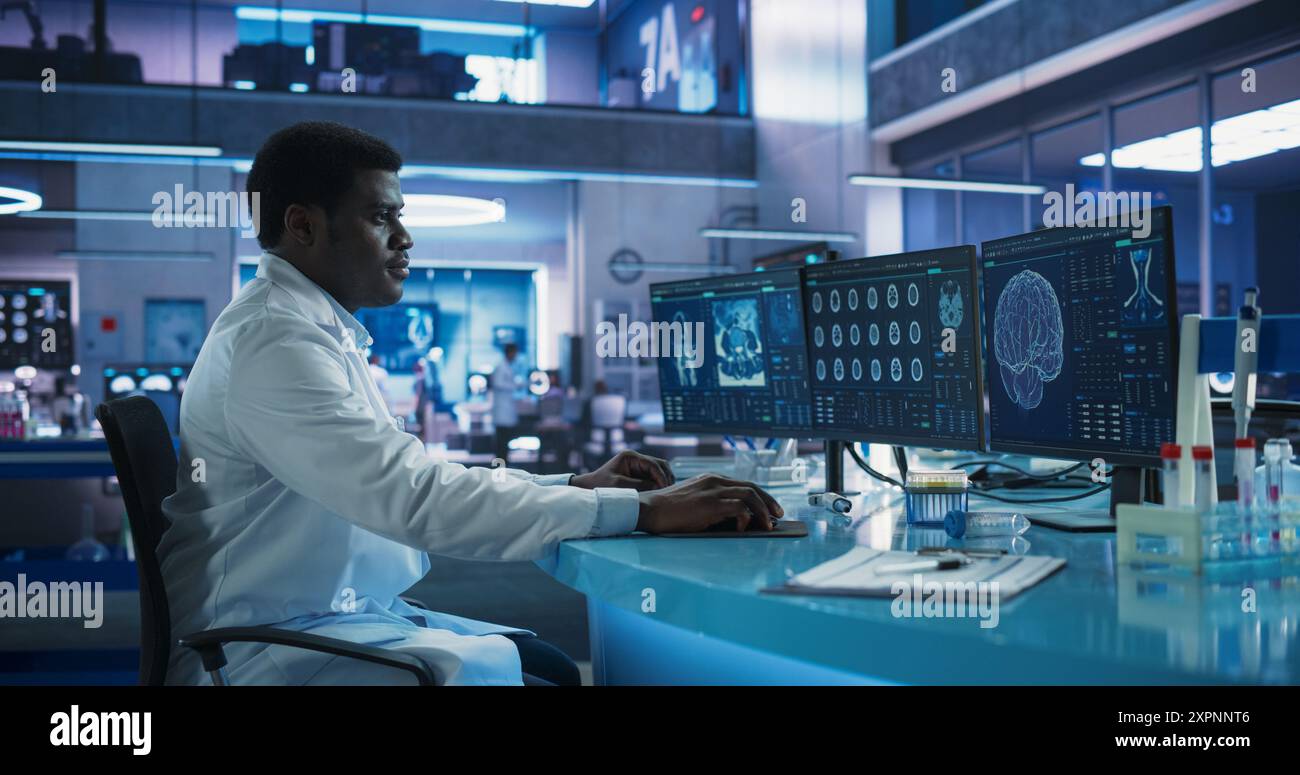 Black Male Neuroscientist Using Desktop Computer To Analyze MRI Scans Of Brain In Medical ...