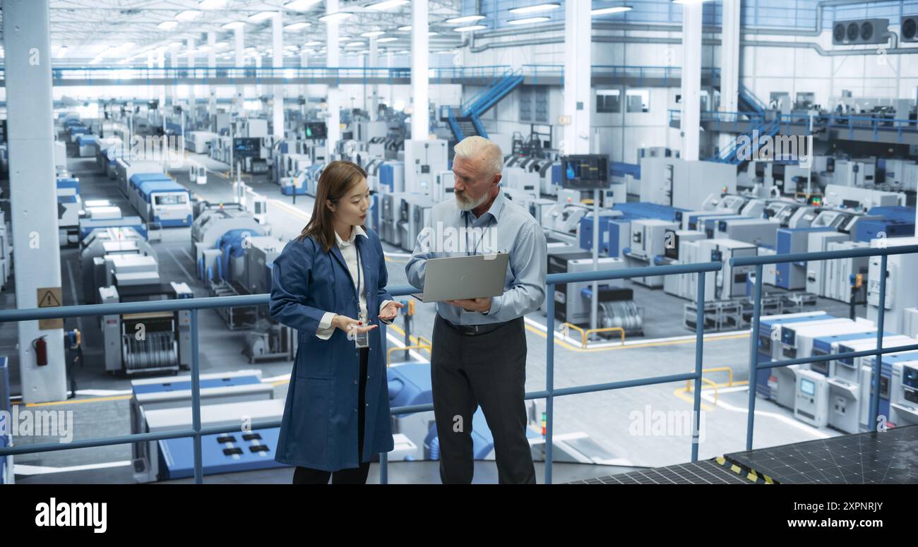 Two Multiethnic Engineers Standing on a Platform, Using Laptop Computer ...