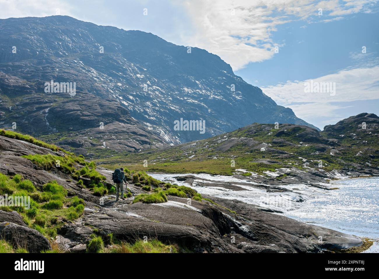 A walker passing the Scavaig river where it empties into Loch na Cuilce ...
