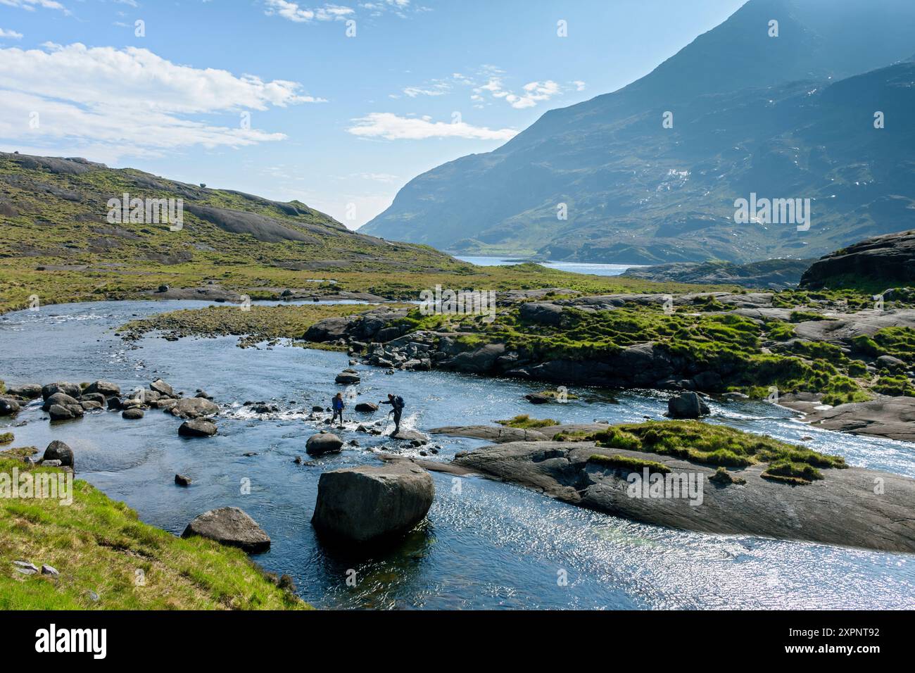 Two walkers crossing the stepping stones over the Scavaig river near ...