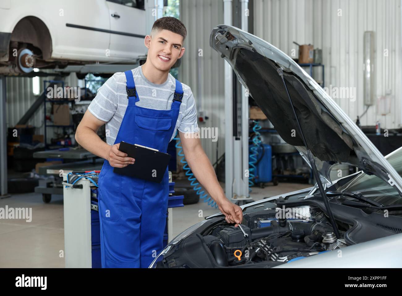 Young auto mechanic taking notes while doing car diagnostic at ...