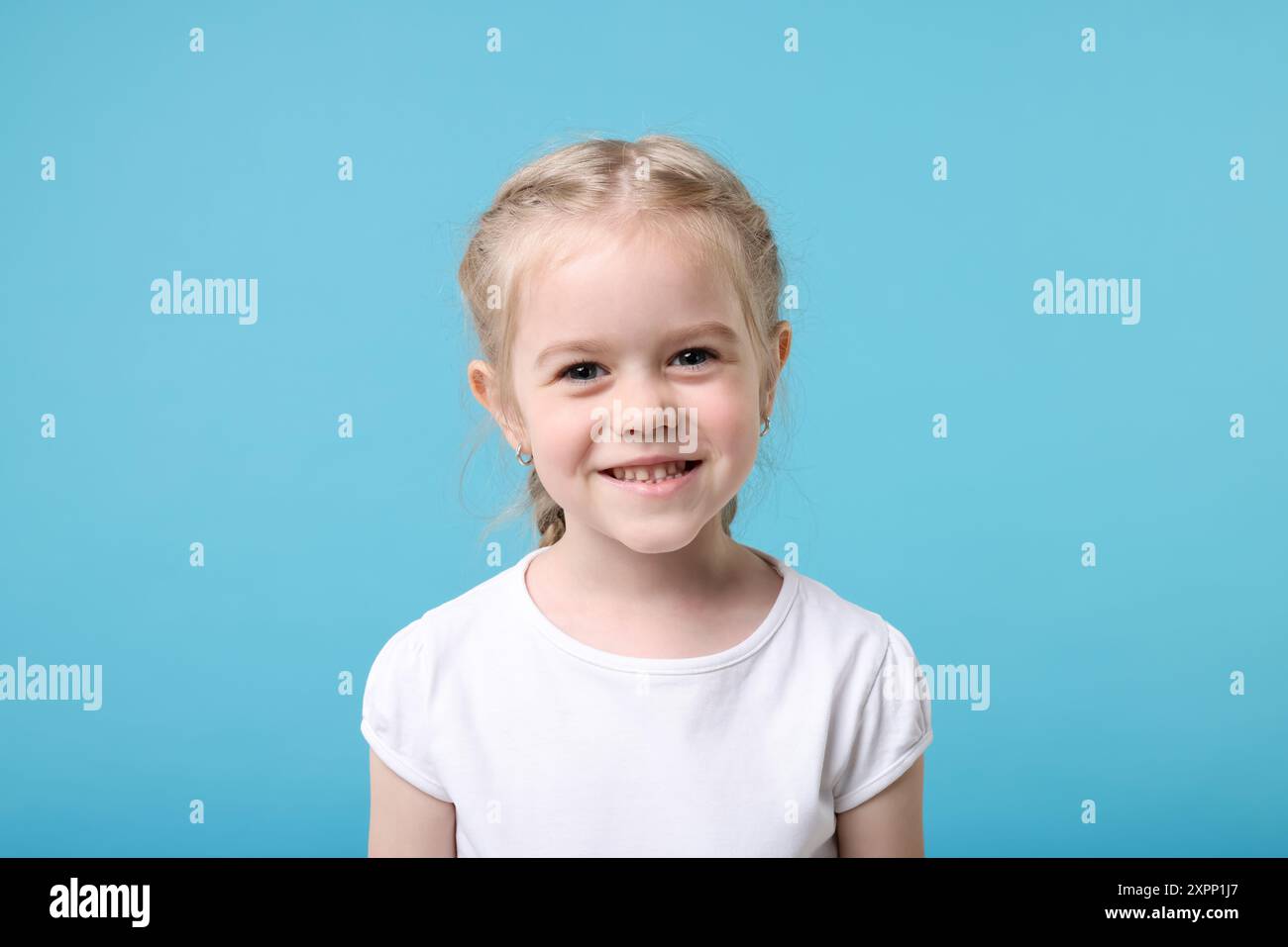 Portrait of cute little girl on light blue background Stock Photo - Alamy
