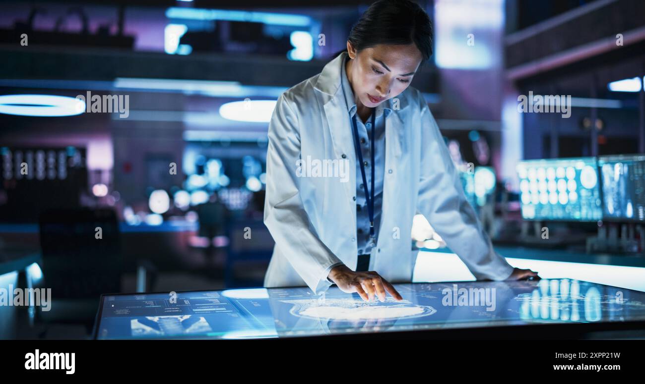 Female Asian Neuroscinetist Using Interactive Touch Screen Table With MRI Scans On Display In ...