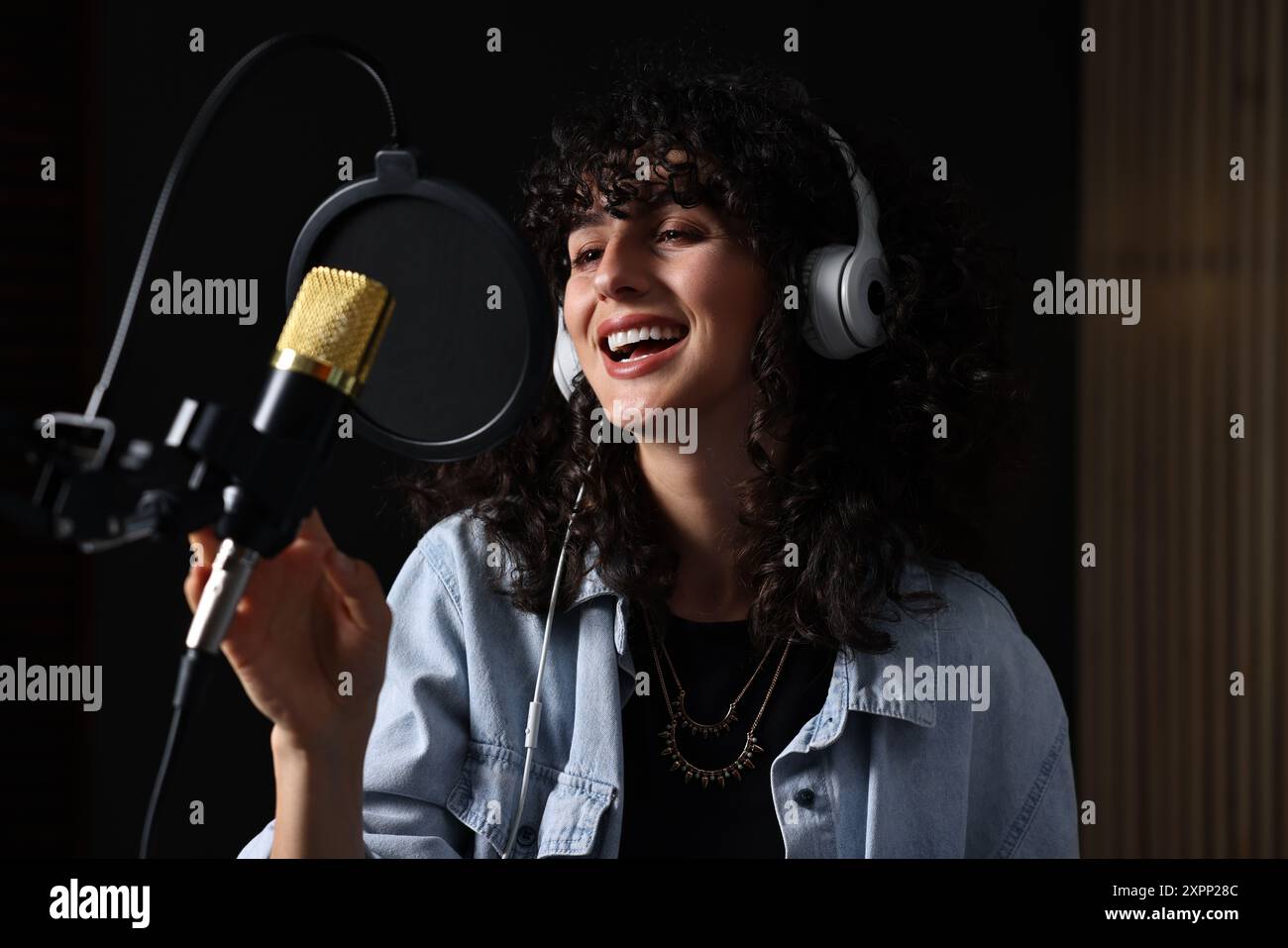 Vocalist with headphones singing into microphone in professional record ...