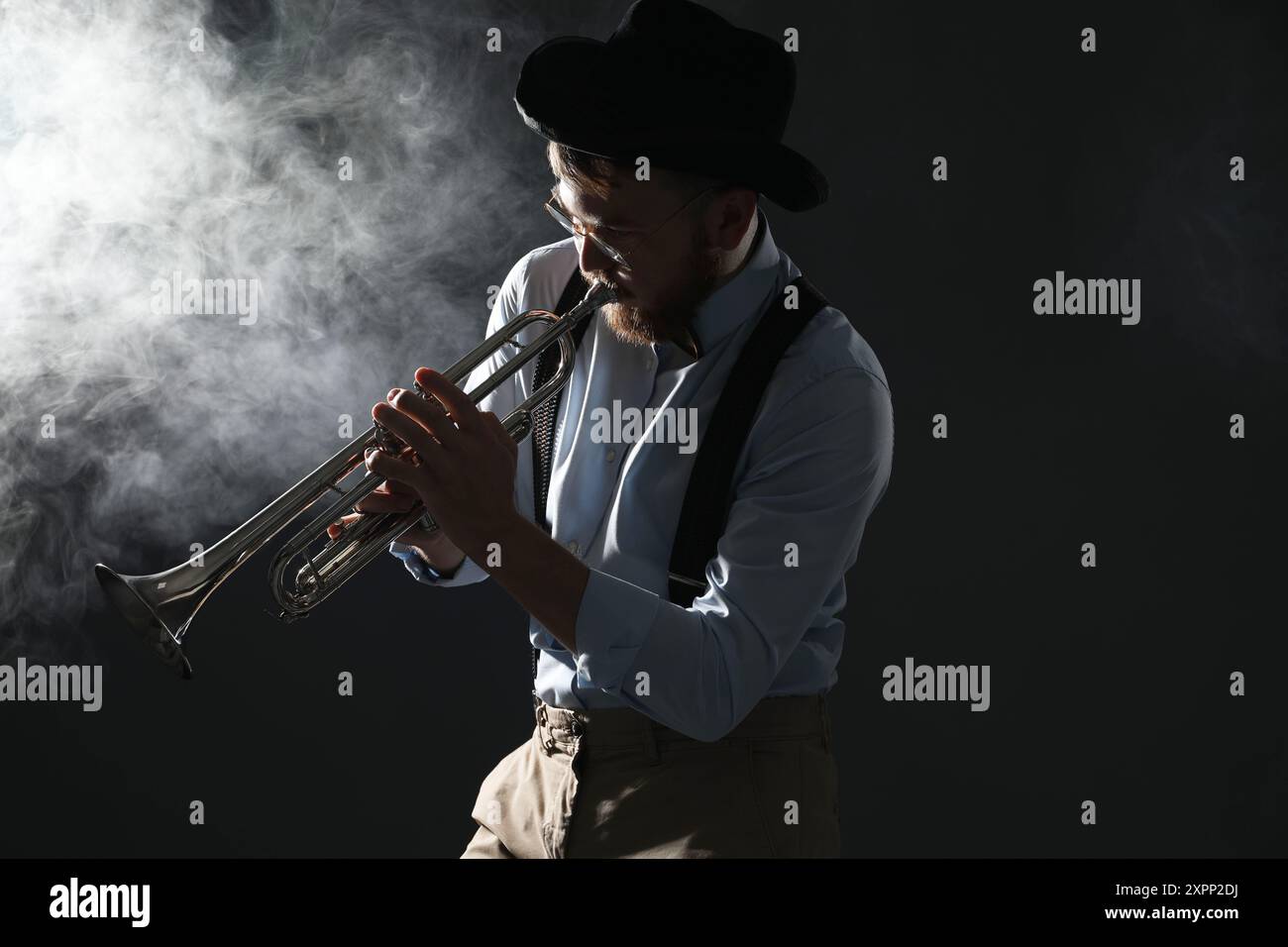 Professional musician playing trumpet on black background with smoke ...