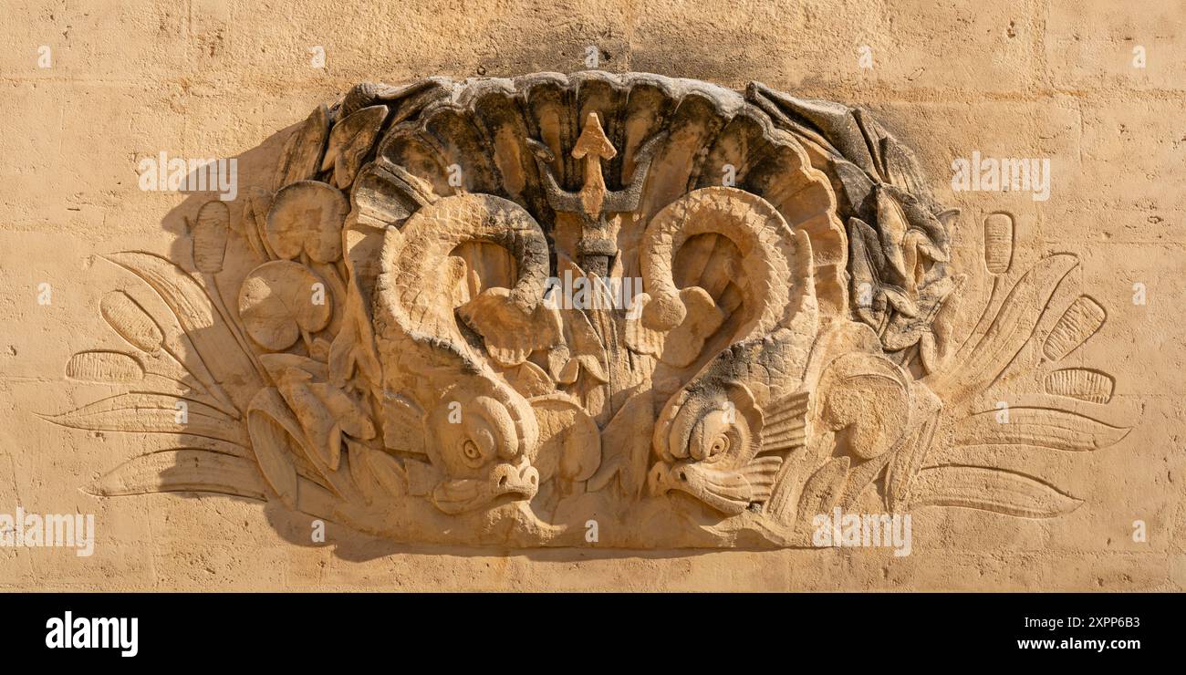 Closeup view of old bas-relief stone carving with shell, dolphins and ...