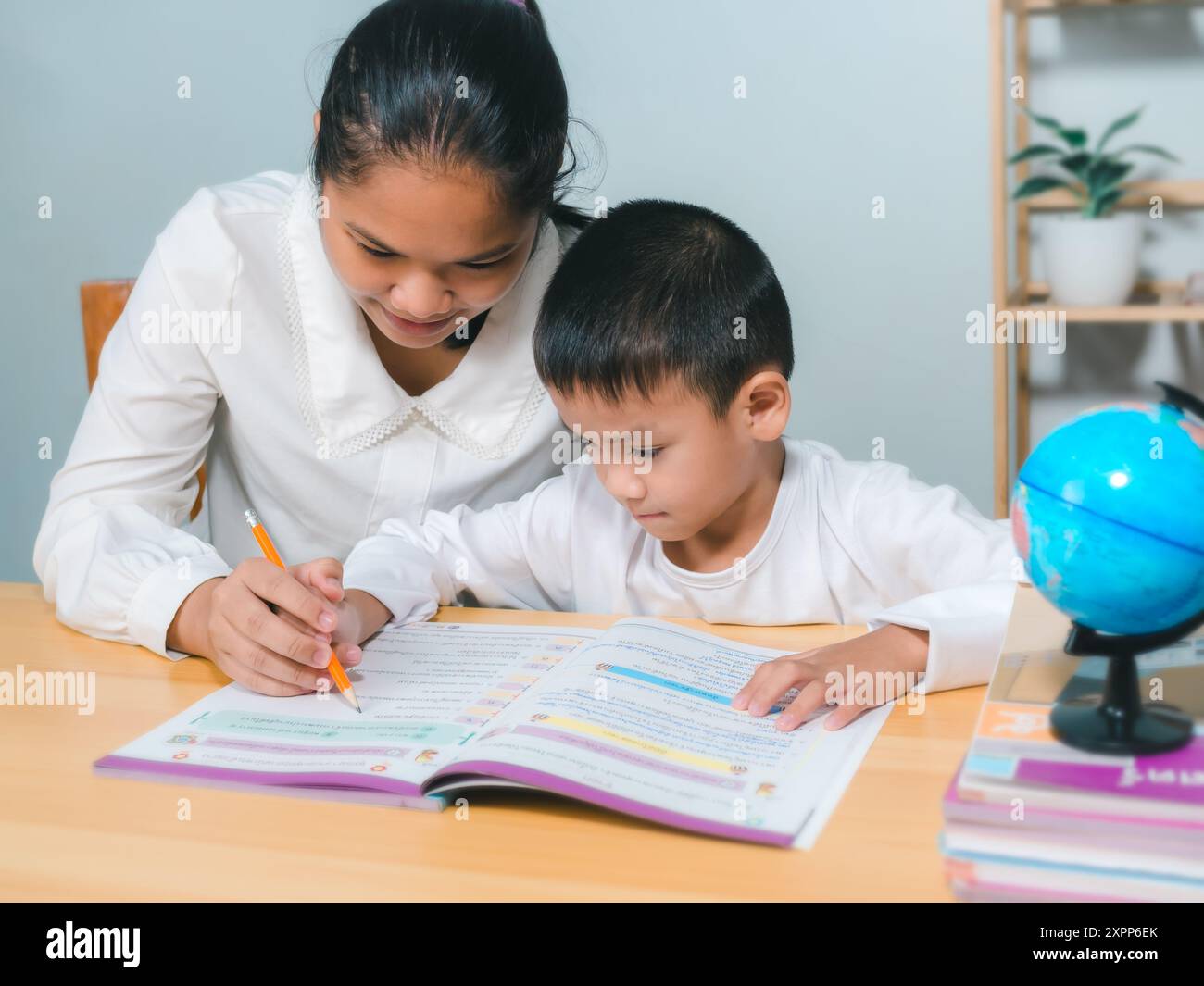 Female tutor helping little elementary school boy with homework during ...