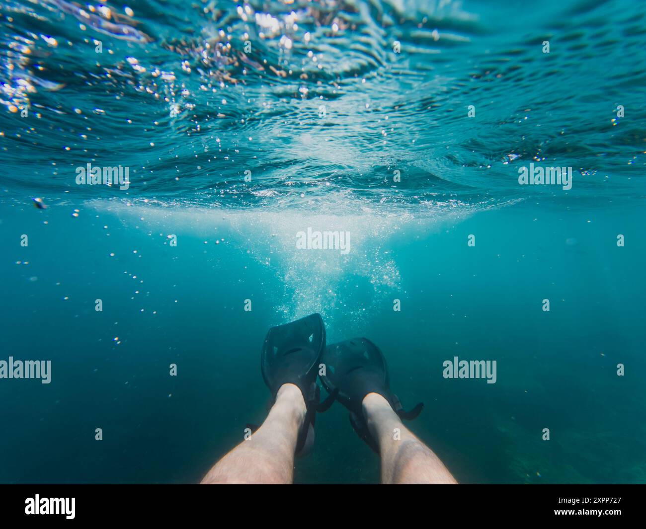 Underwater photo from an action camera, male legs with black fins in ...