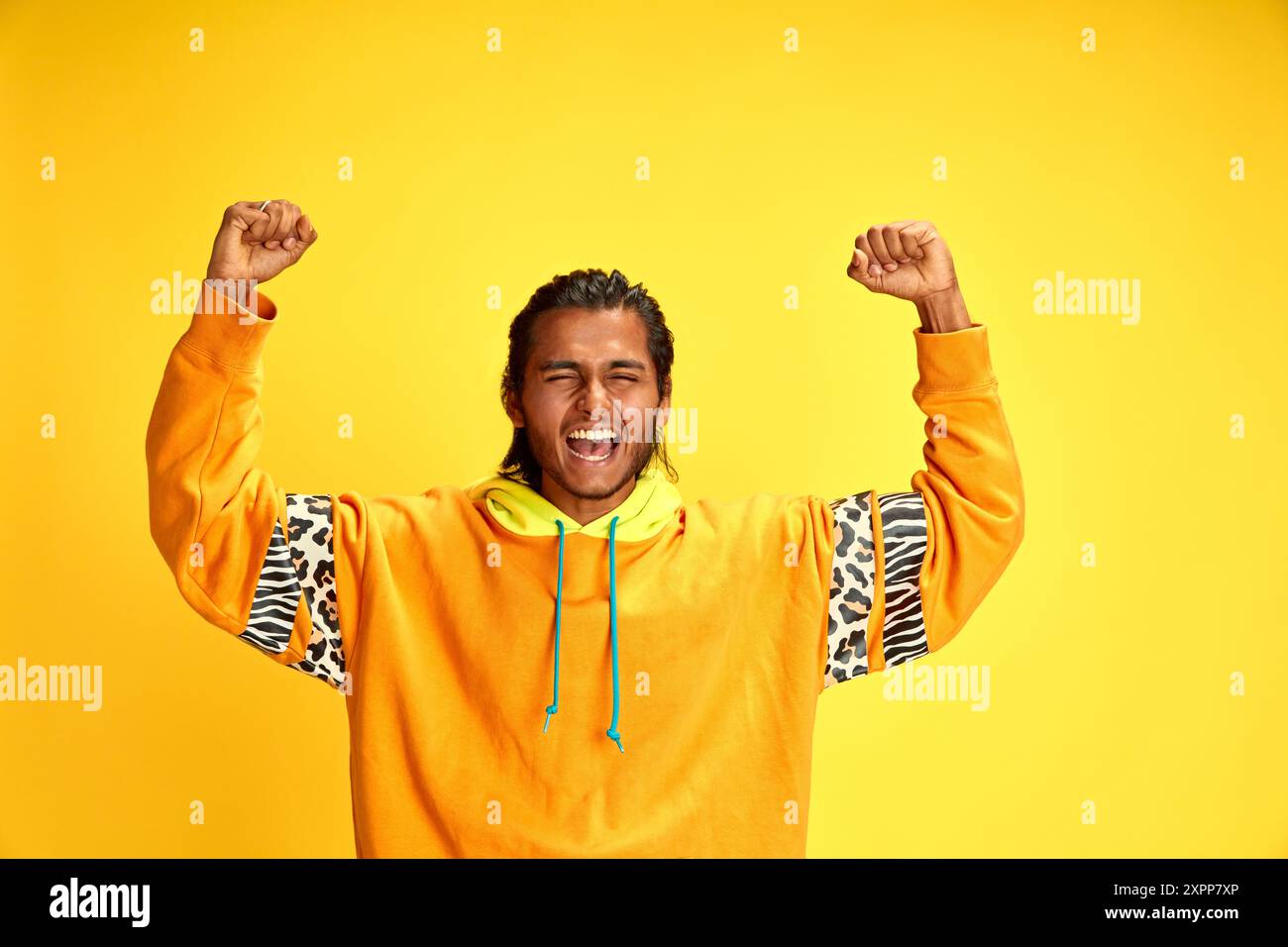 Overjoyed young Indian man raising hands of happiness and screaming of ...