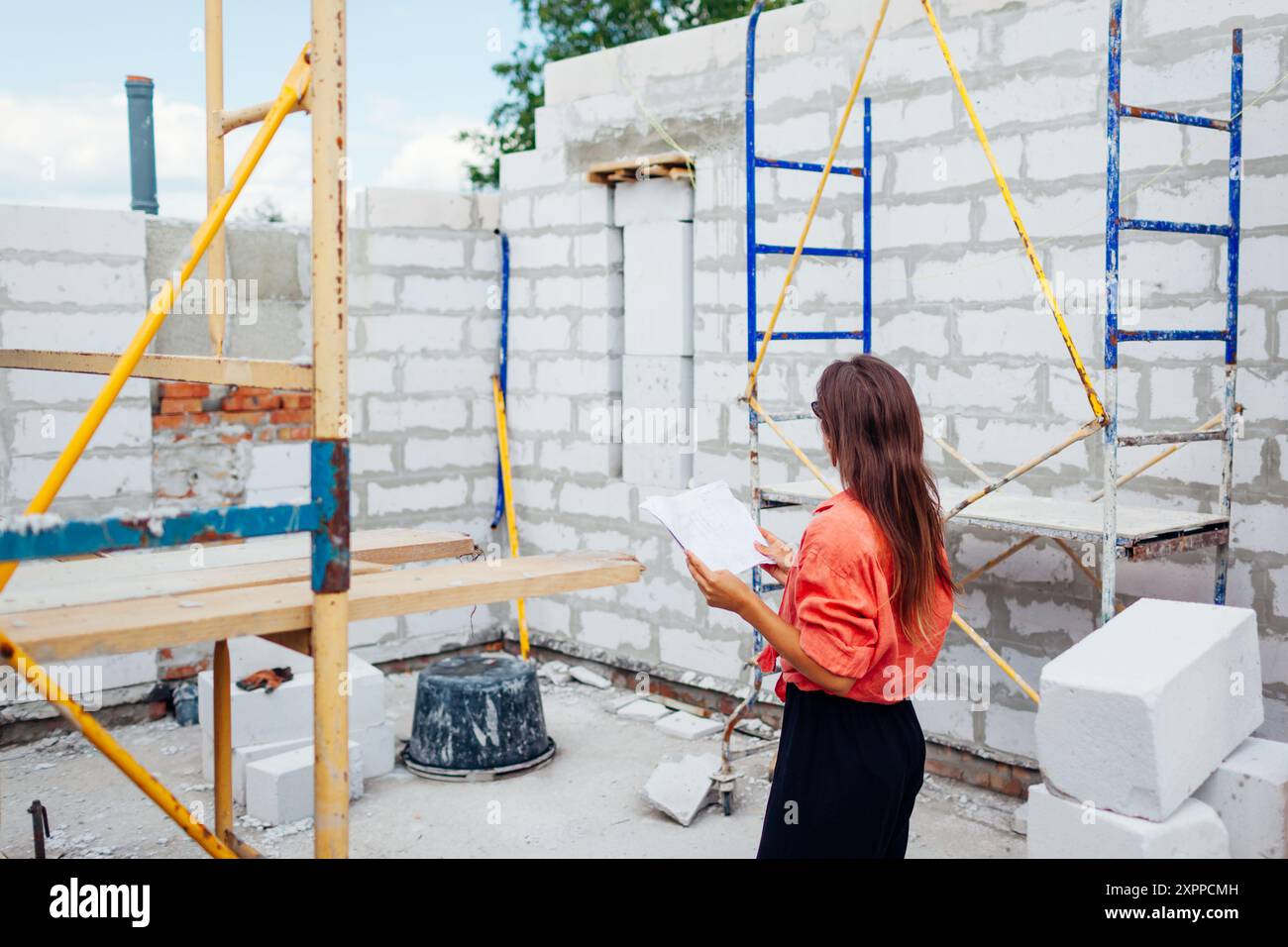 Back view of young woman checking her house under construction standing ...