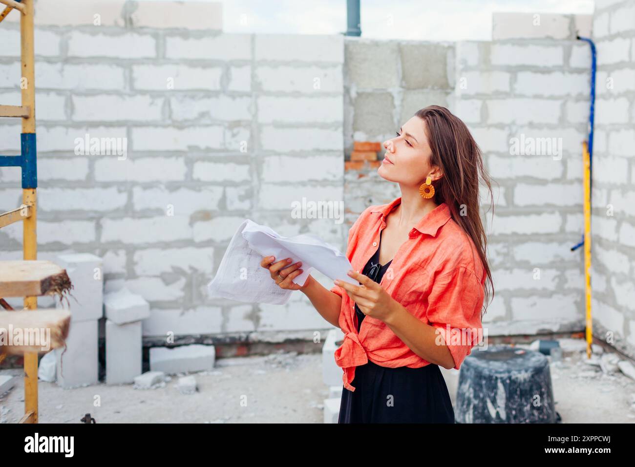 Happy young woman checking her house under construction comparing ...