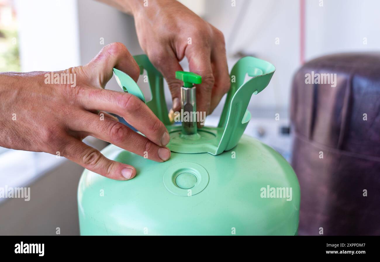 Technician hands adjusting valve on refrigerant tank during air ...