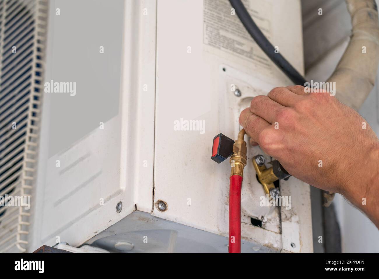 Technician's hand adjusting connections on outdoor air conditioner unit ...