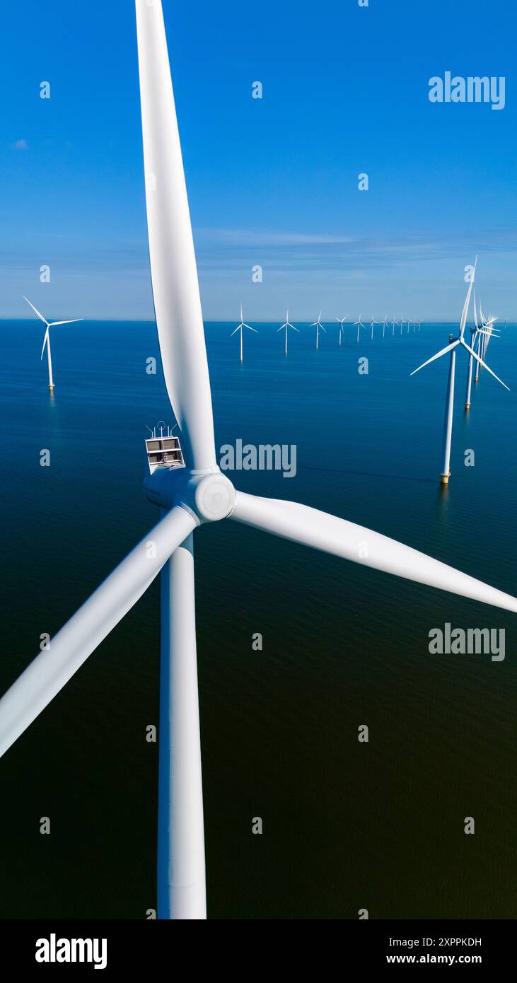 Giant wind turbine blades spin gracefully, harnessing wind energy amidst the vast blue expanse ...