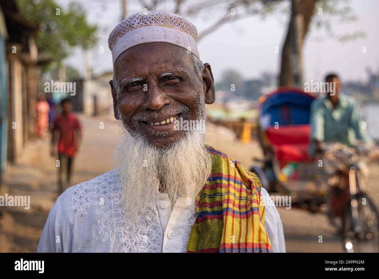 Portrait of smiling man with white beard and cycle rickshaw behind ...