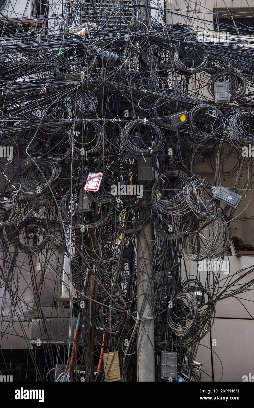 Absolutely chaotic but functioning collection of power lines on a mast in front of a high-rise ...