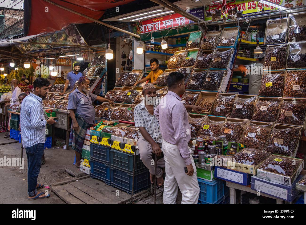 Men stand in front of a market stall selling dates, Barisal (Barishal ...