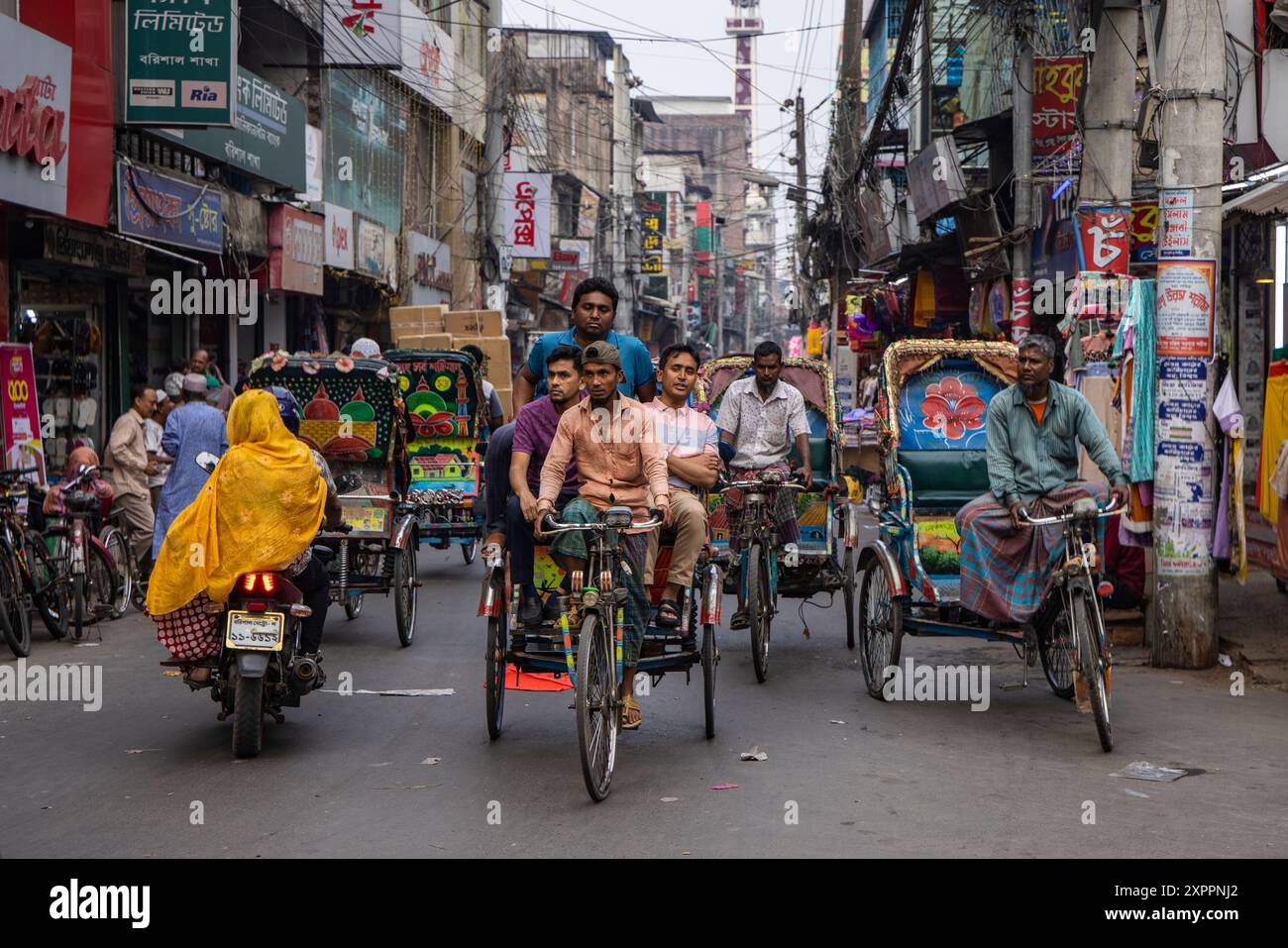 People ride cycle rickshaws on a downtown street, Barisal (Barishal ...