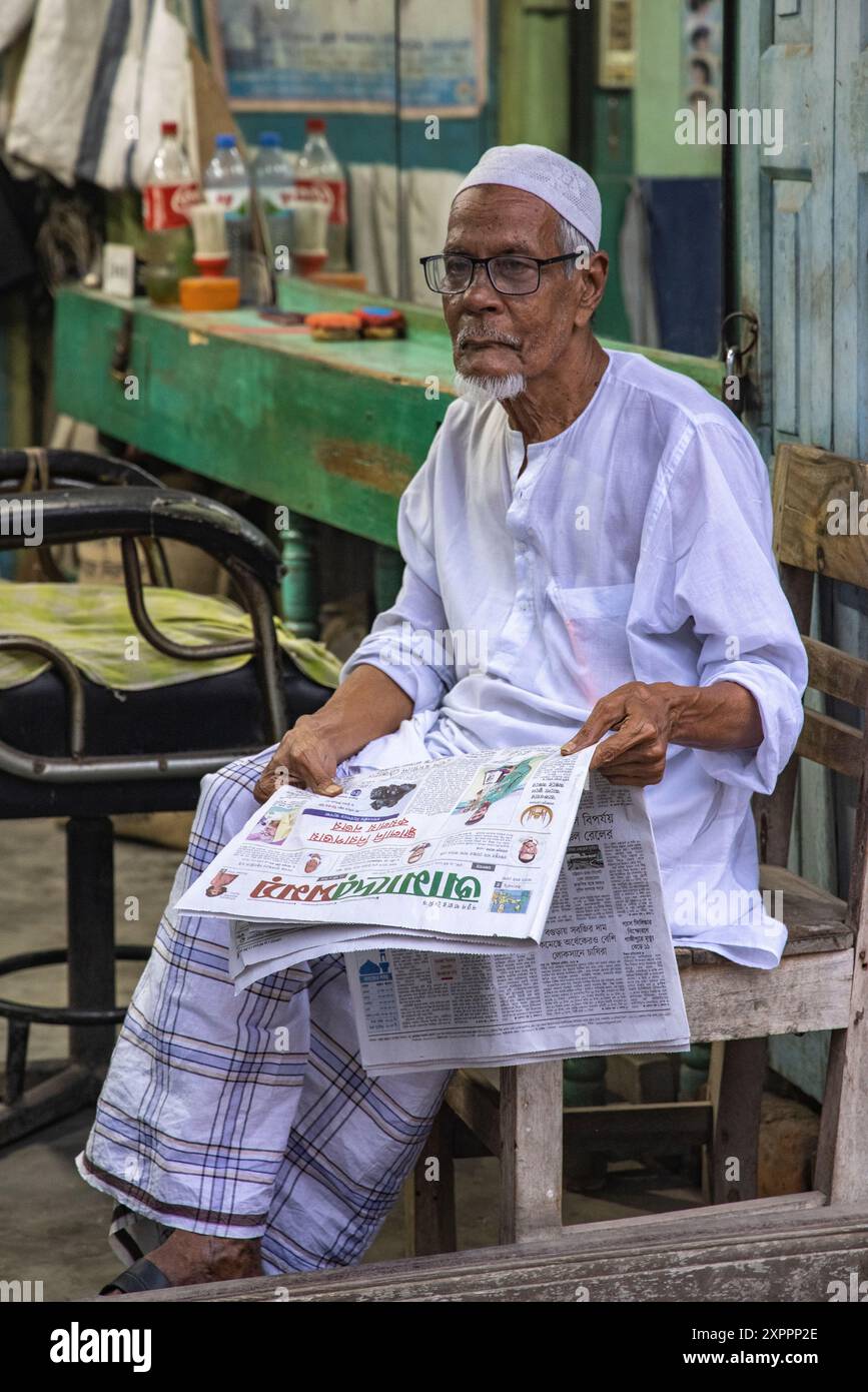 Elderly man with newspaper in barber shop, Kaukhali (Kawkhali ...