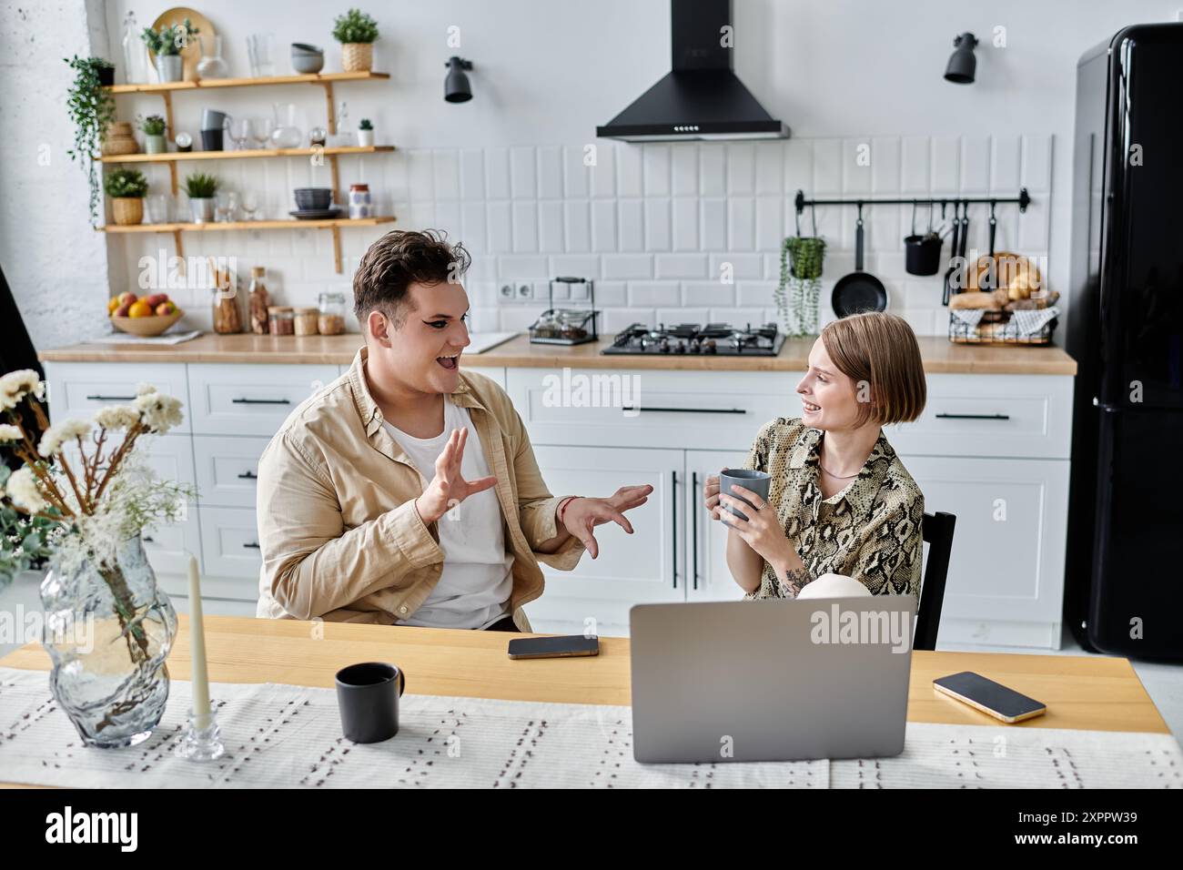 Two friends share laughter and stories in a cozy kitchen Stock Photo ...