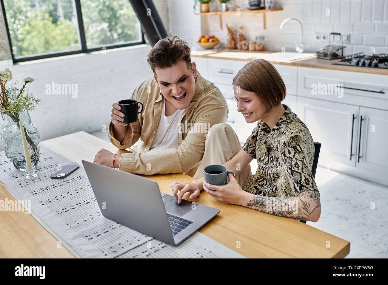 Two friends share laughter and connection over coffee and a laptop ...