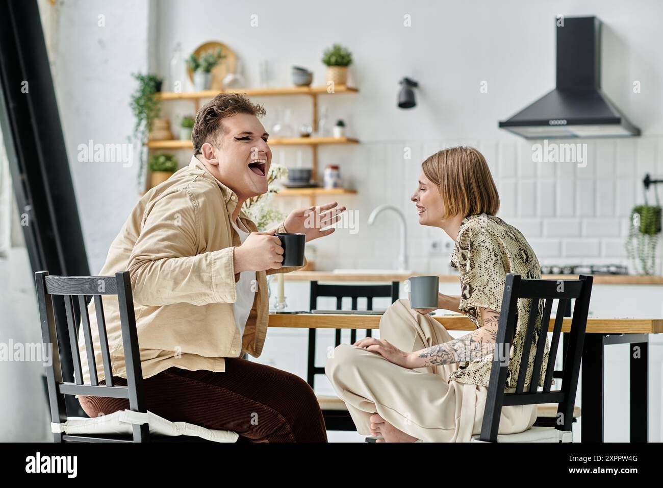 Two friends share laughter and coffee in a chic home environment Stock ...