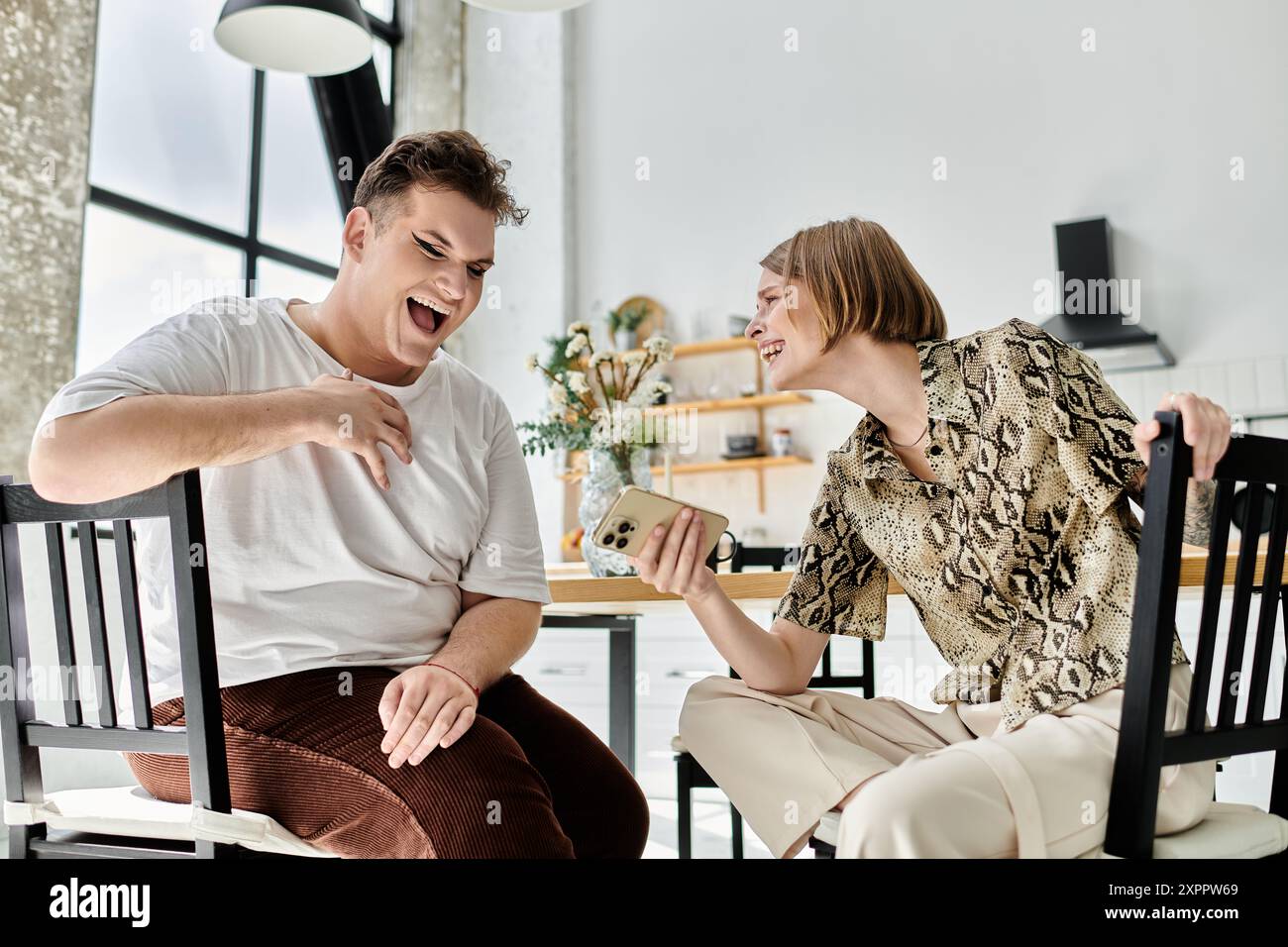 Two friends laughing together while sharing a fun moment at home Stock ...