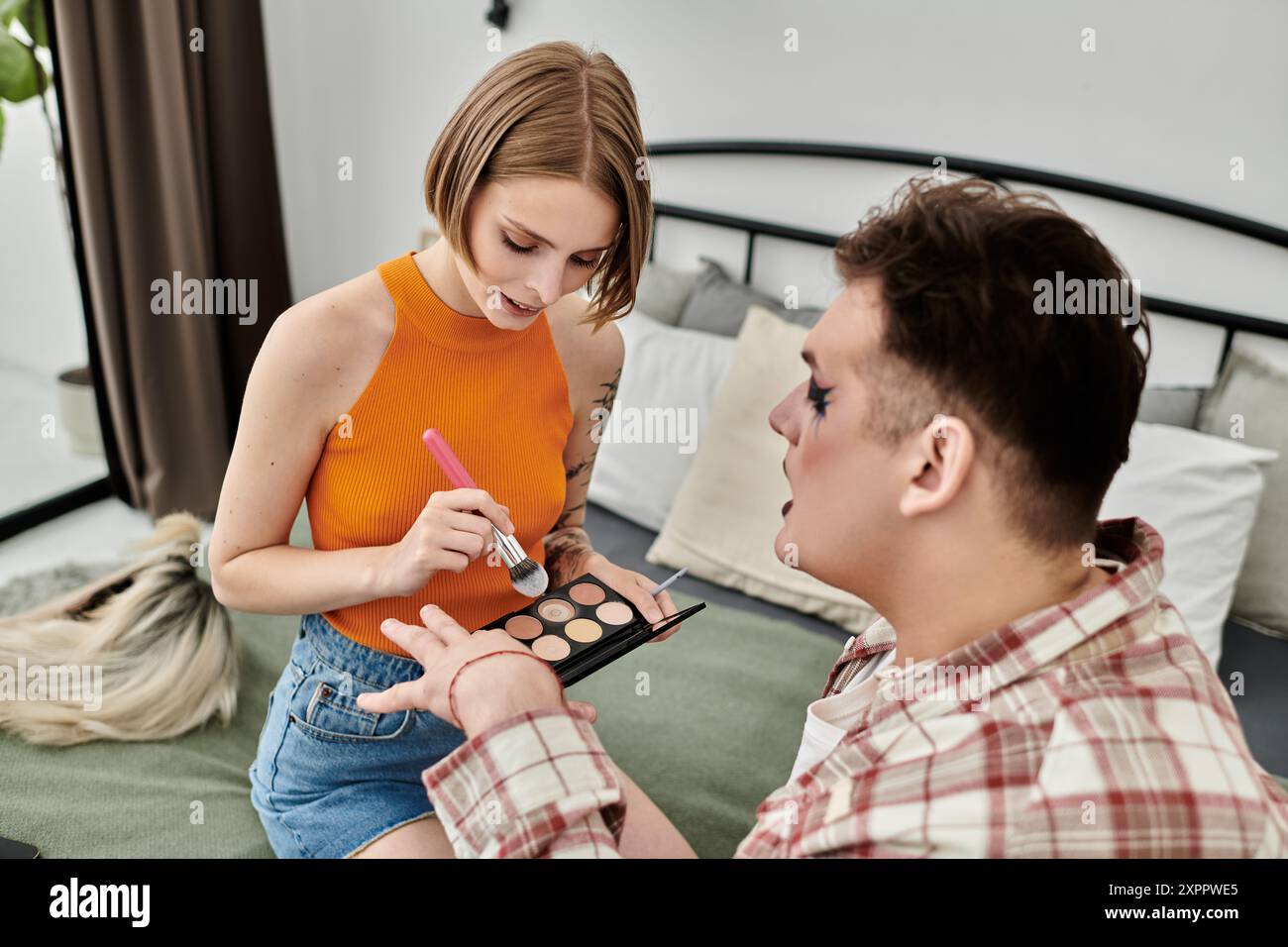 A stylish individual receives makeup application from a friend in a ...