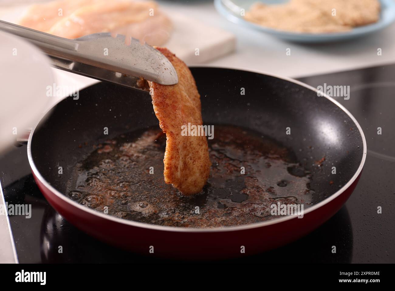 Cooking schnitzel in frying pan on stove, closeup Stock Photo - Alamy