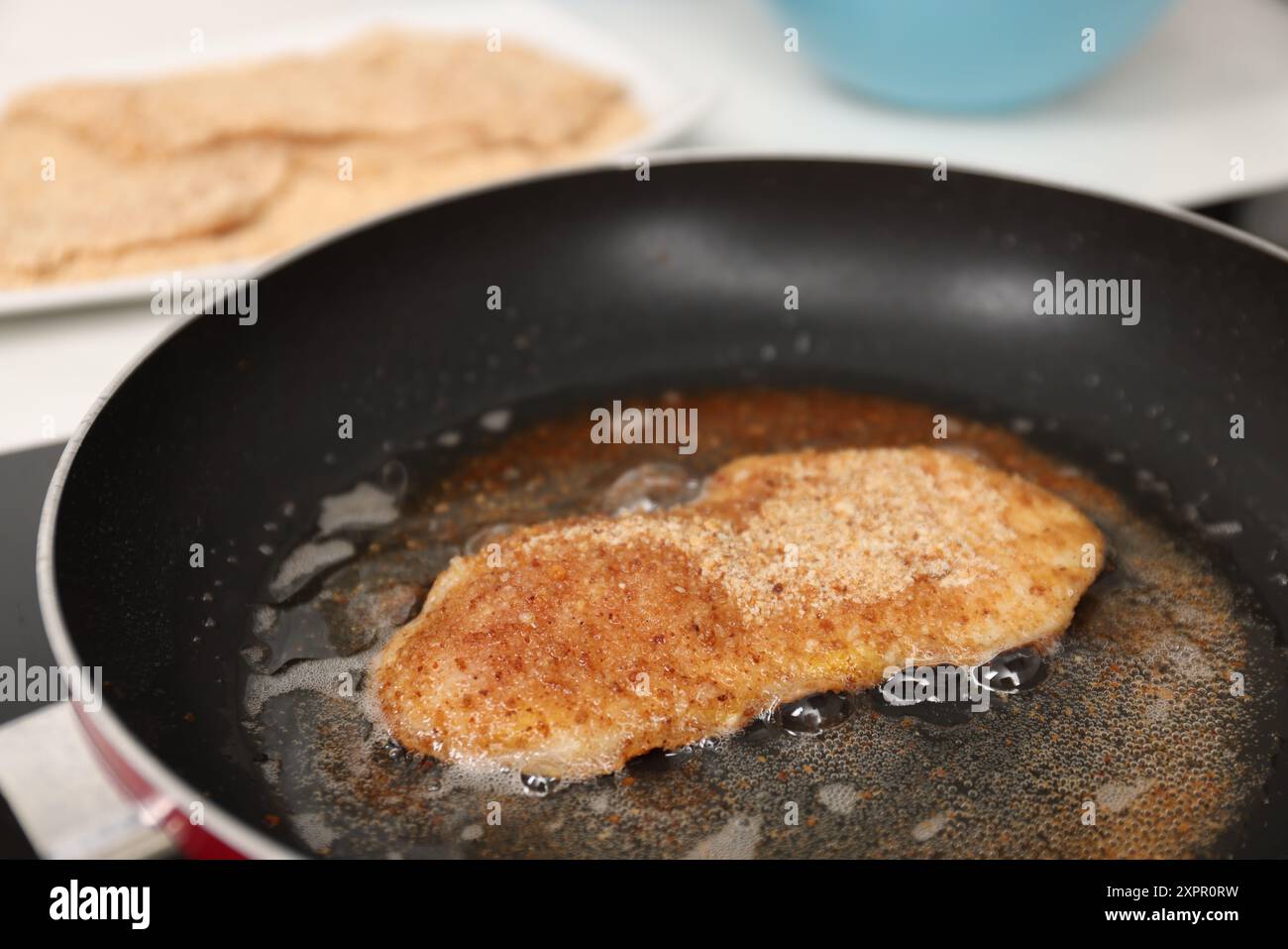 Cooking schnitzel in frying pan on stove, closeup Stock Photo - Alamy