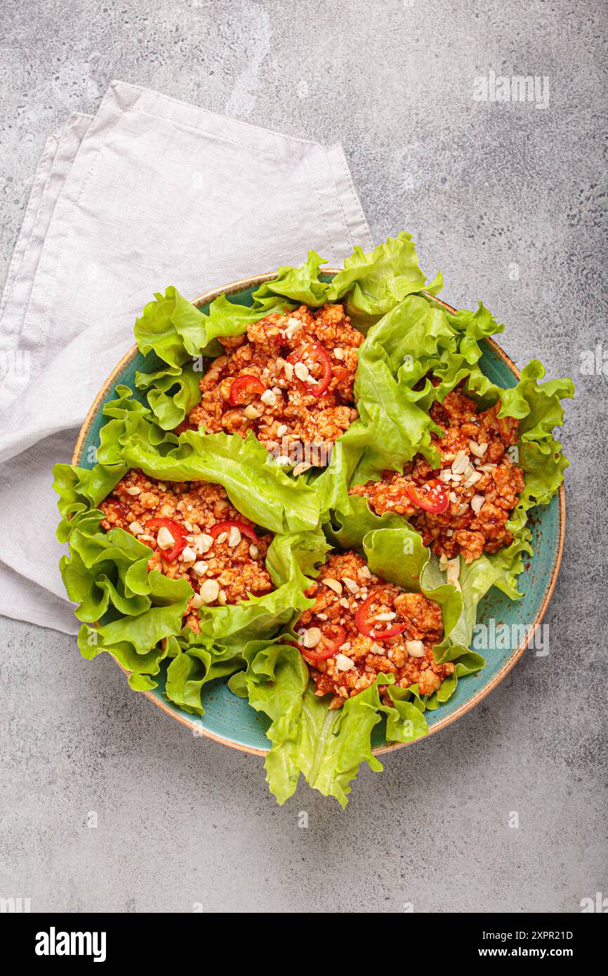 Lettuce wraps filled with minced meat and topped with peanuts and chili ...