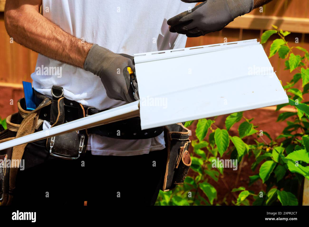Workers cut plastic vinyl siding to size using scissors prior to ...