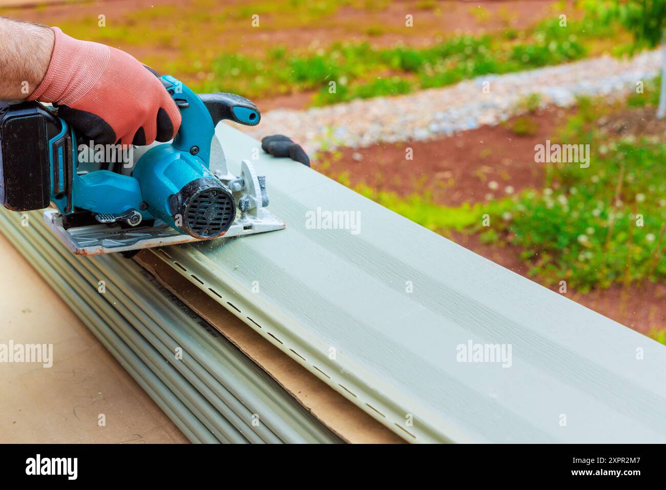 Worker cut plastic vinyl siding to required size with circular handsaws ...