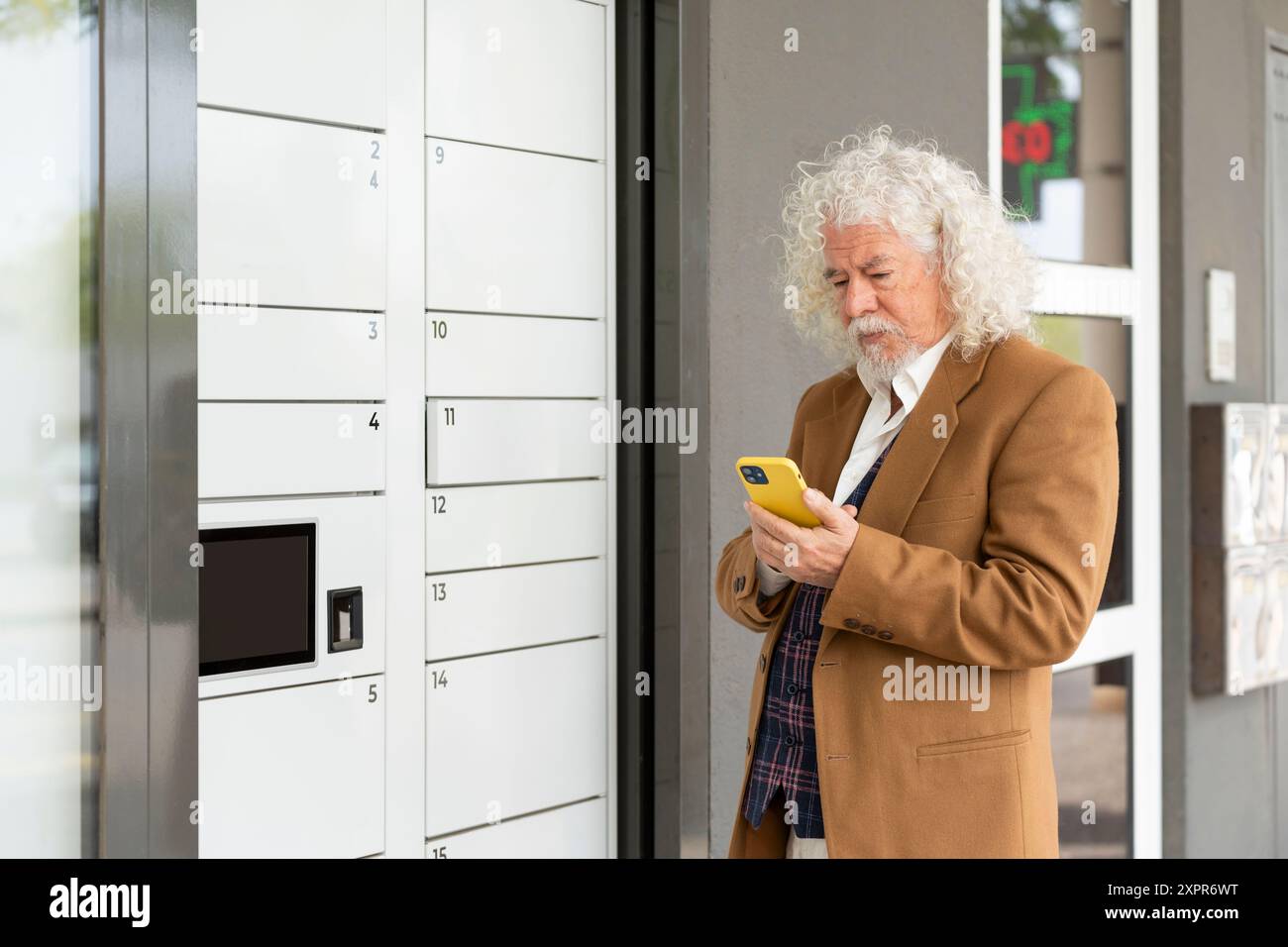 Older man with a package at a locker, looking his smart phone Stock ...