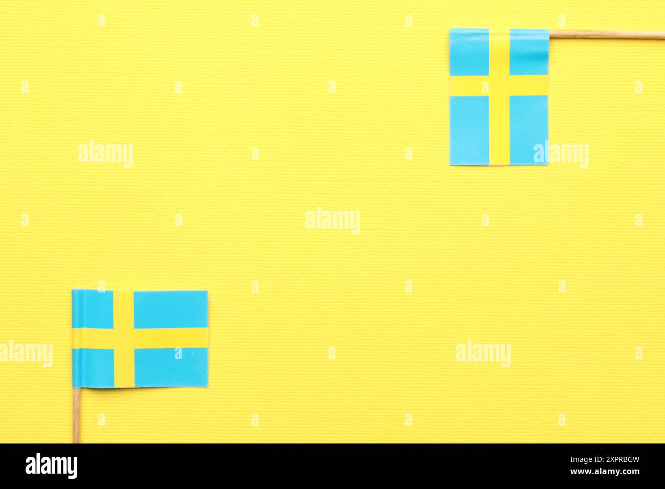Small paper flags of Sweden on yellow background, top view. Space for ...
