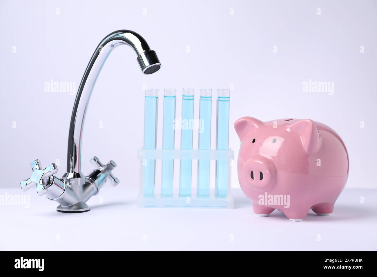 Water saving concept. Piggy bank, tap and test tubes with liquid on ...