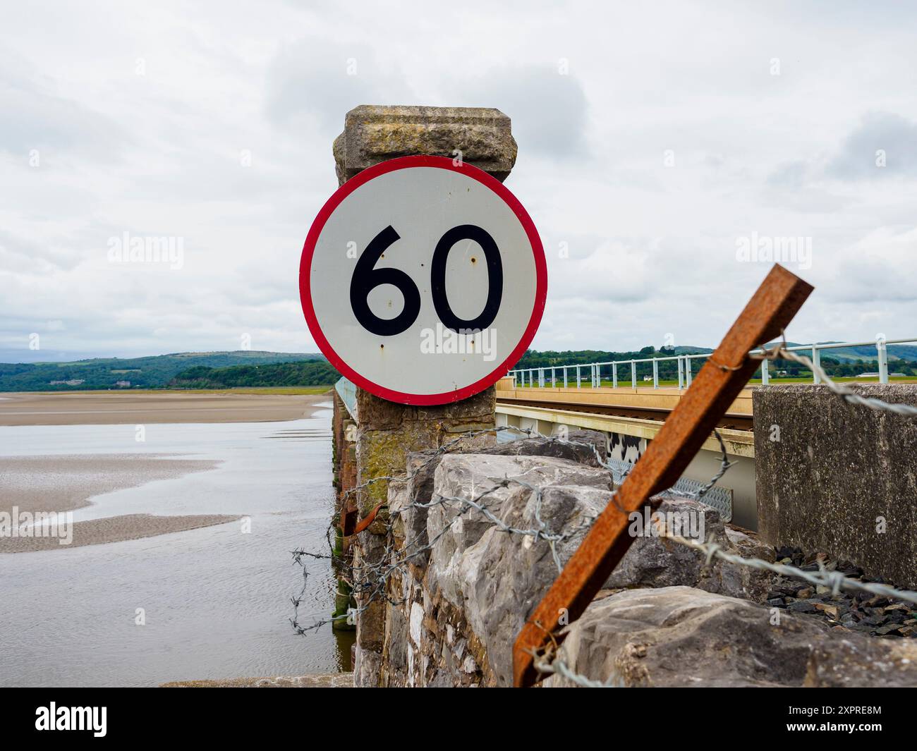 A 60 mph speed limit sign on a scenic coastal bridge with a stone ...
