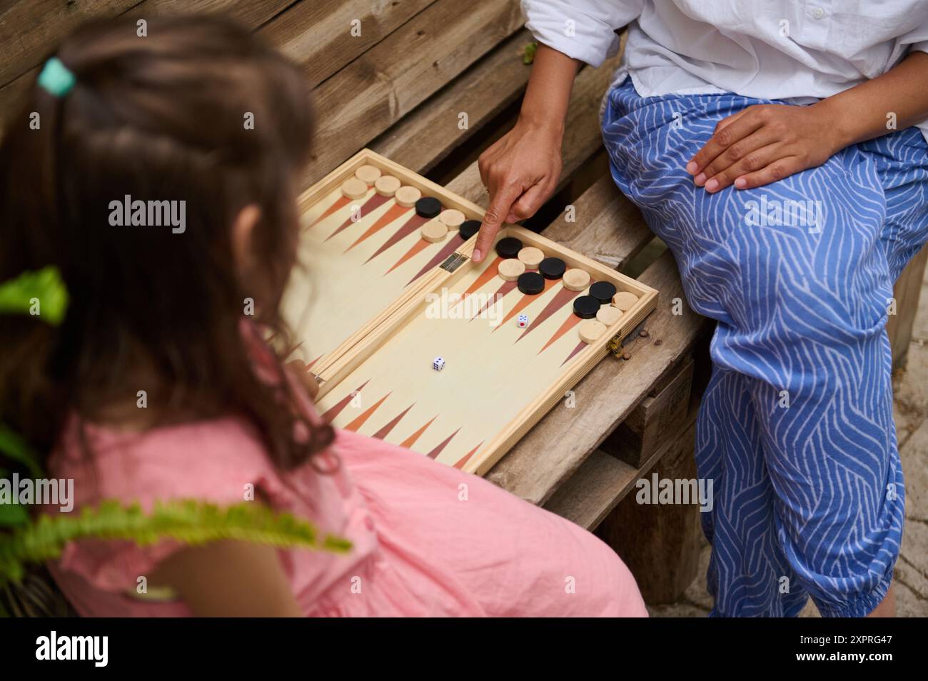 Two people having fun playing backgammon outside on a rustic wooden ...