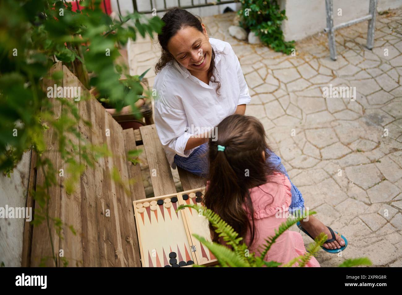 A mother and daughter sharing a joyful moment while playing backgammon ...