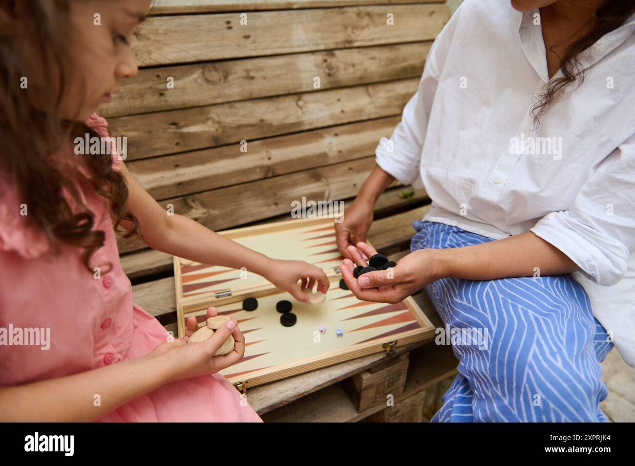 Mother and daughter bonding over a game of backgammon outdoors. The ...