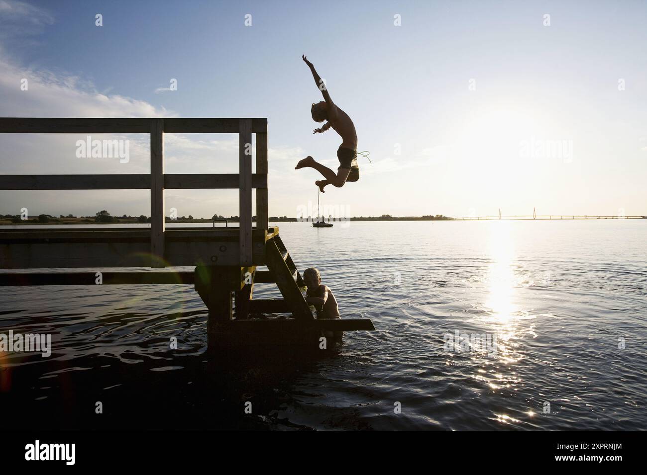 Boys leaping off a pier in Denmark Stock Photo - Alamy