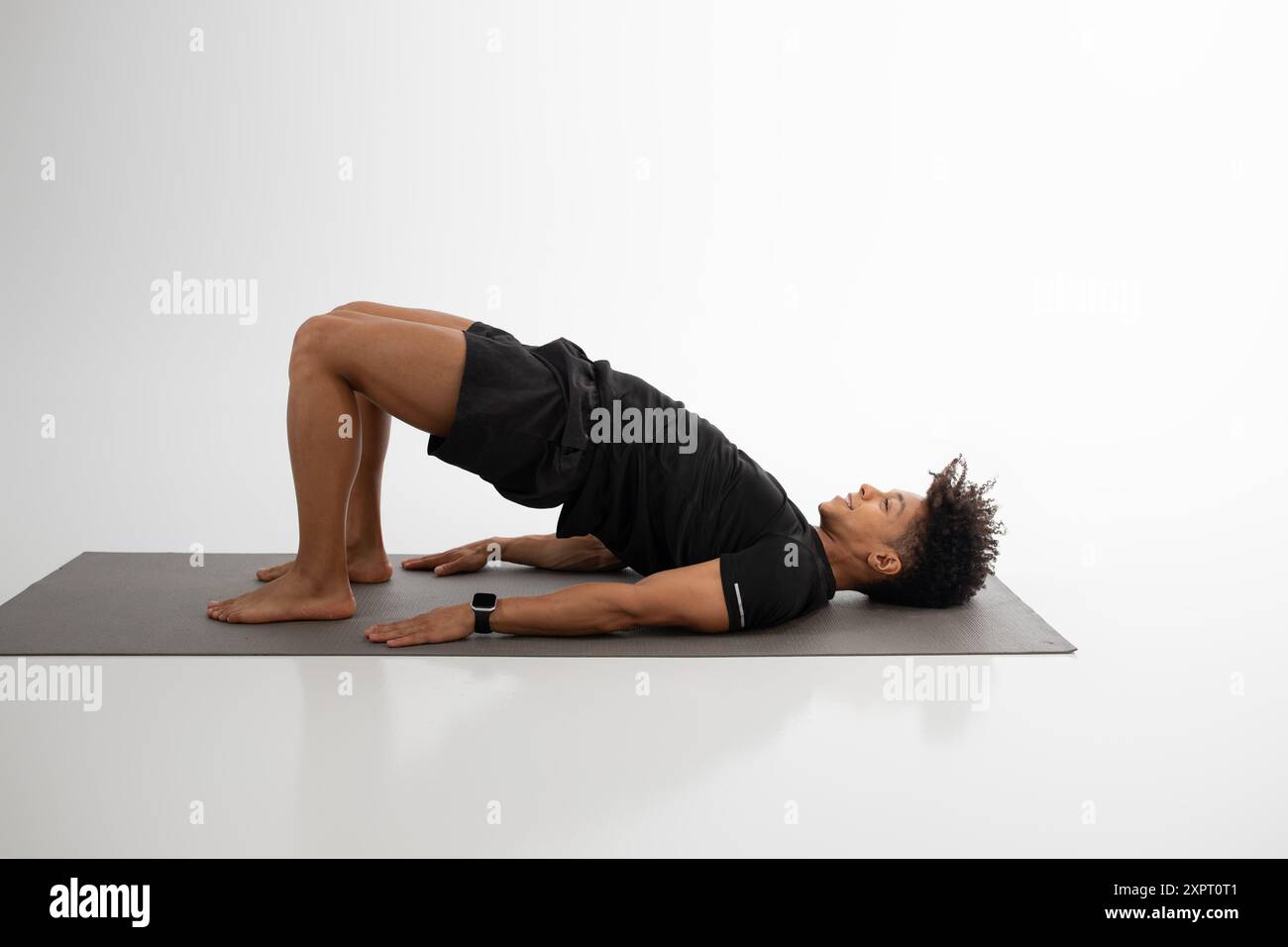 Man Performing Bridge Exercise on Yoga Mat In Studio Stock Photo - Alamy