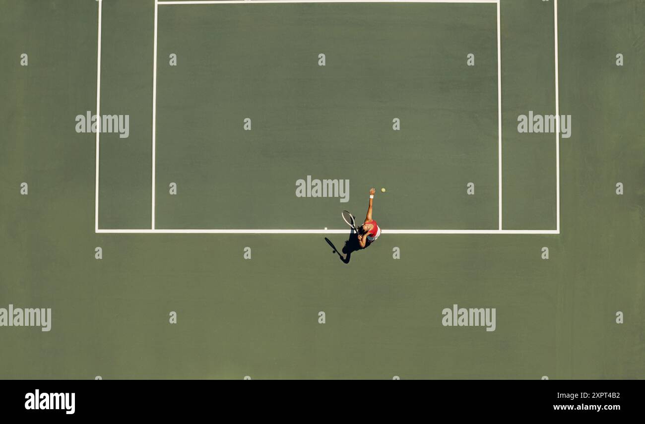 Aerial view of a tennis player serving on a court during a match on a ...