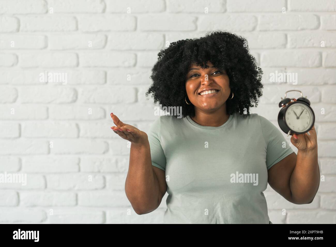 Surprised african american woman holding alarm clock amazed with open ...