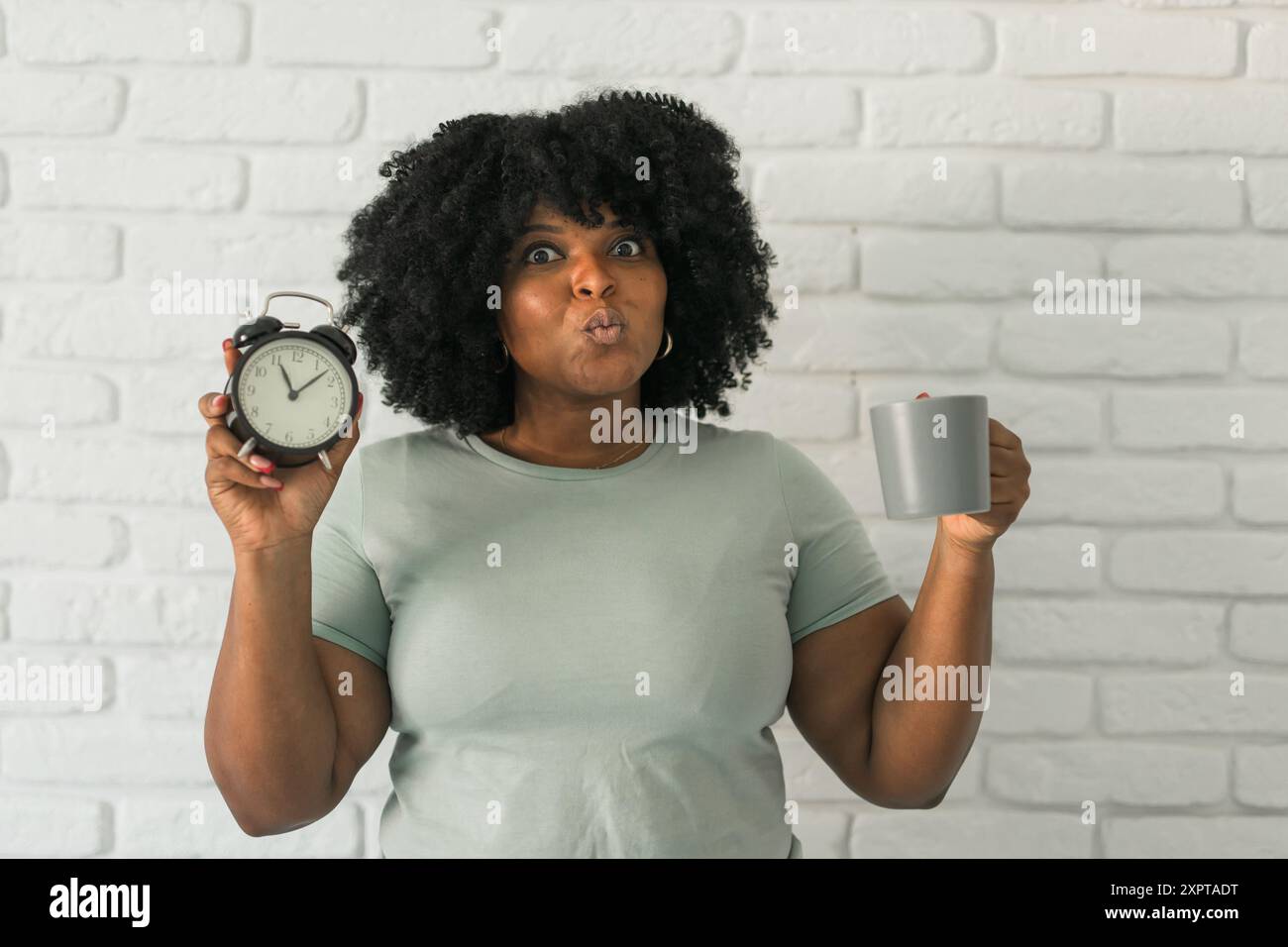 Surprised african american woman holding alarm clock amazed with open ...