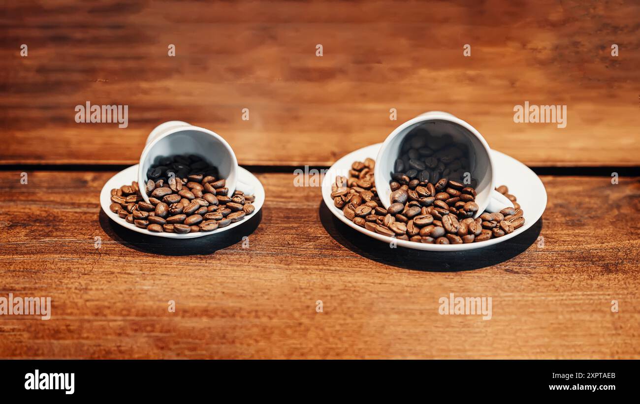 Two ceramic cups spill roasted coffee beans on a rustic wooden surface ...