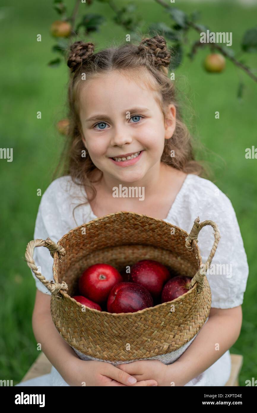 Cute little curly girl with long hair and blue eyes in white dress is ...