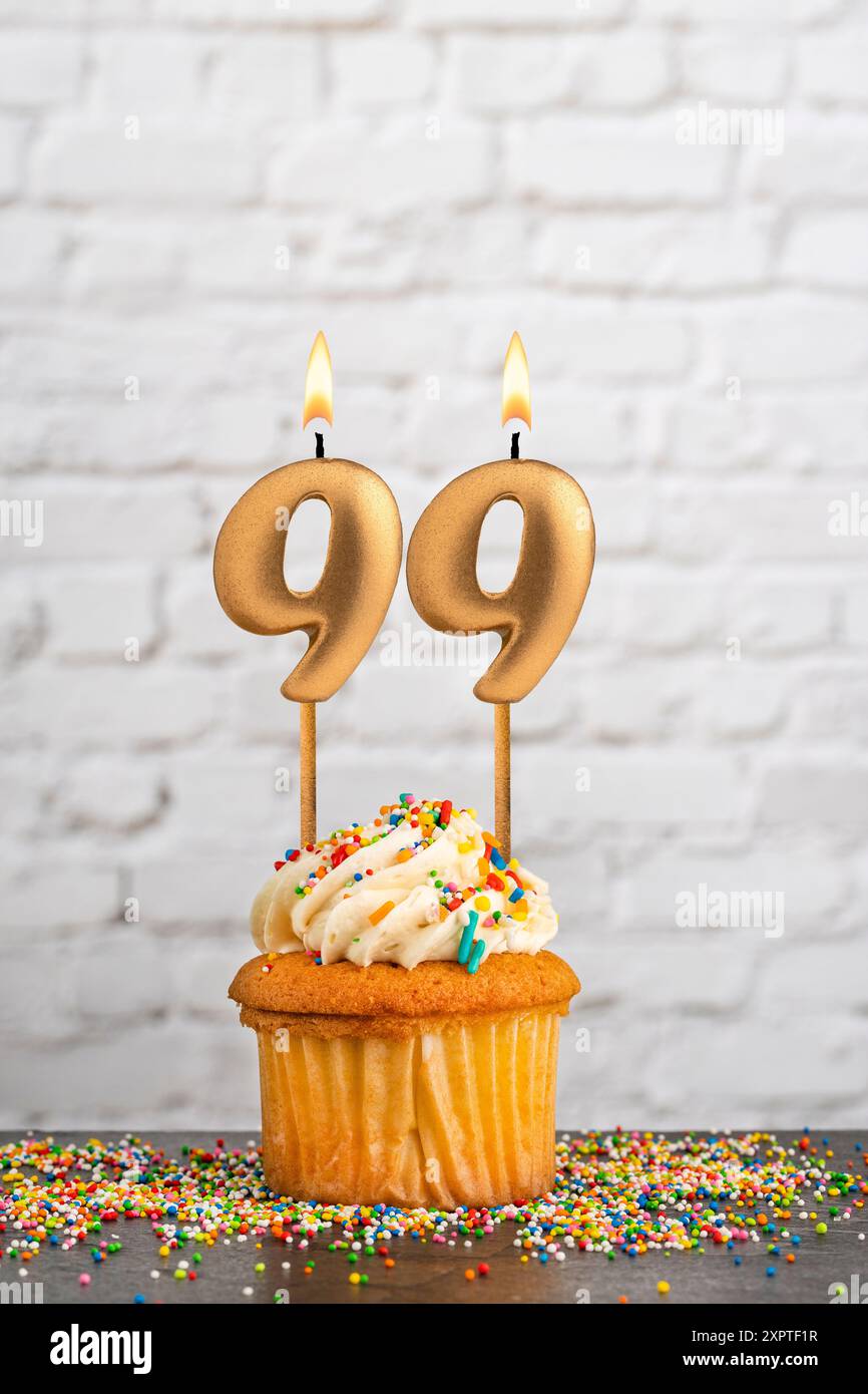 Golden birthday candle number 99 with cupcake - White block wall ...